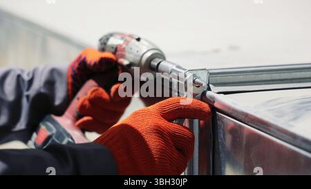 Worker use power tools to secure metal roofing panels on building under ...