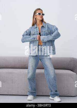 Blonde woman showcases her trendy denim outfit with stylish eyewear in ...