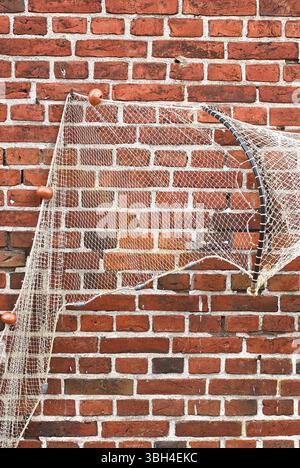 Old fish trap (fyke net) in front of a red brick wall – traditional ...