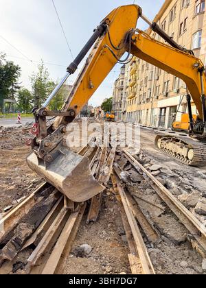 Excavator removing old tram rails at sunset. Urban transportation ...
