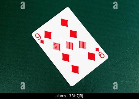 A vintage nine of diamonds playing card isolated on a black background ...