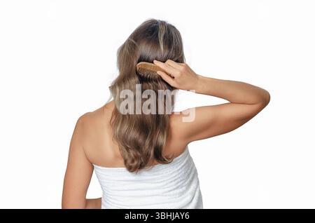Combing woman's wavy hair after shower with wooden comb on white ...