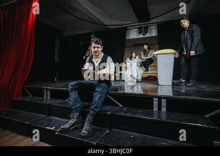 Young actors performing a dramatic scene on a dimly lit theater stage ...