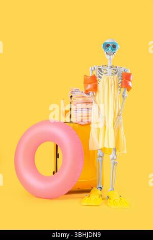 Human skeleton, beach accessories and suitcase on yellow background ...