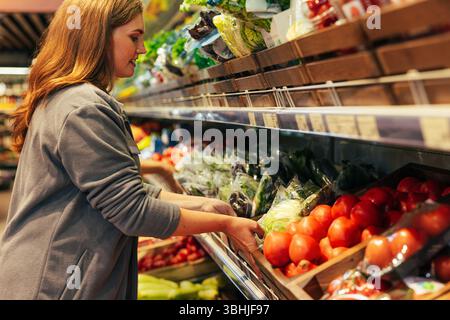 Female grocery store worker refreshing products on the shelf, moving a ...