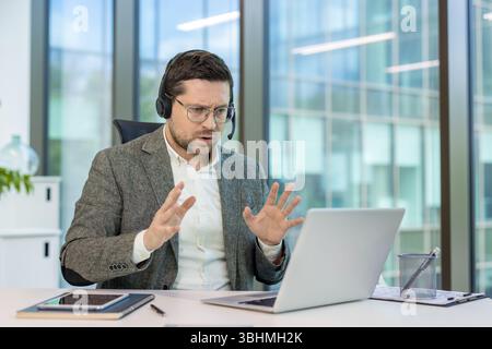 confused remote operator in headset showing shrug gesture while sitting ...
