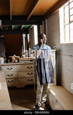 Wood artisan smiling, wearing apron in workshop, working with ...
