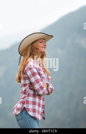 Smiling blonde woman wears denim outfit and poses confidently against a ...