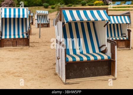 Neatly arranged white lounge chairs and blue beach umbrellas on a sunny ...