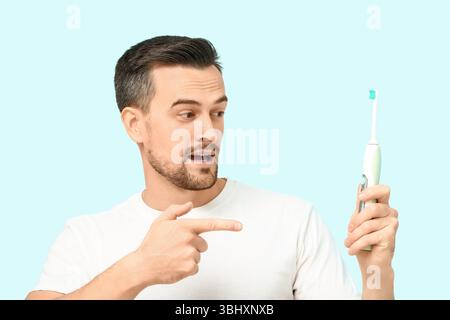 Young man pointing at toothbrush on color background Stock Photo - Alamy