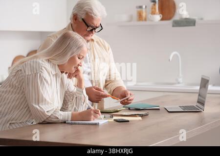 Senior couple calculating utility bills in kitchen Stock Photo - Alamy