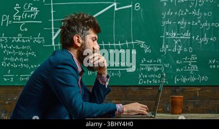 Teacher explains math at blackboard. Professor in classroom with ...