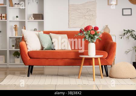 Comfortable sofa and coffee table with dahlia flowers in vase in living ...