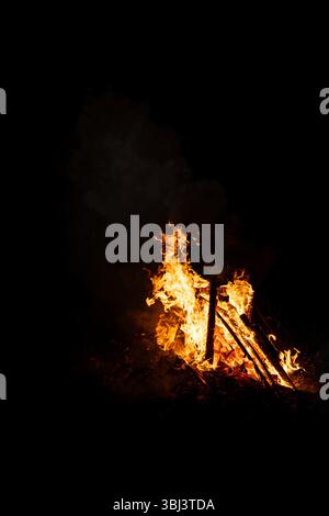 smoke from the flames of the fire and a wooden pole burning vertically ...