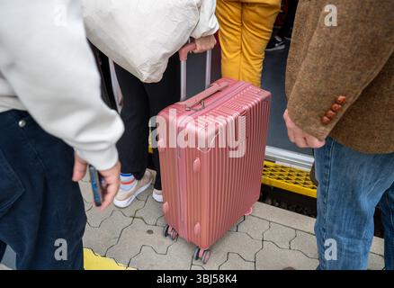 Pink carry on suitcase standing near airport glass doors. Travel ...