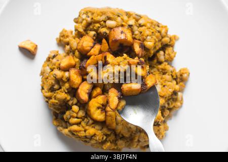 Overhead view of nigerian fried beans and fried plantain on a white ...