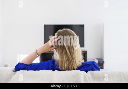 Woman is waiting for a movie to load on the TV. Slow Internet ...