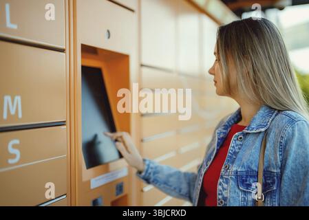Woman picks up mail from automated self-service post terminal machine ...
