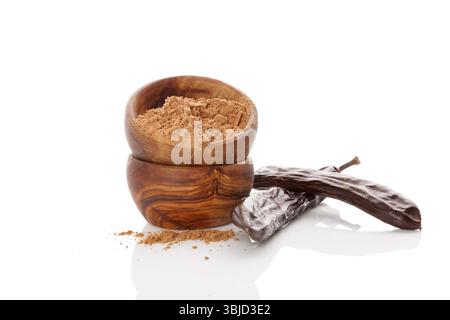 Carob pod and powder in wooden bowl isolated on white background with ...