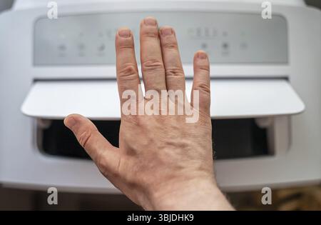 Male hand checking air flow of floor standing mobile air conditioner ...