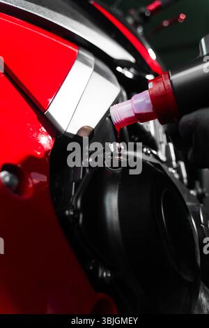 Precision oil fill operation on a red sportbike to ensure proper engine ...