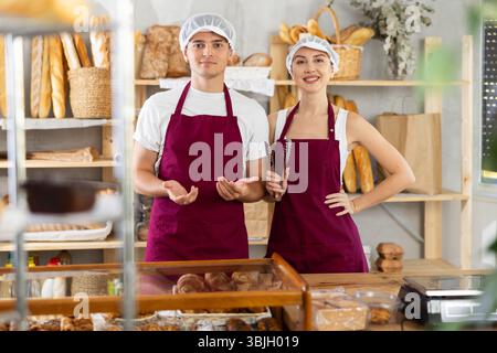 Young woman and guy sellers at counter in bakery Stock Photo - Alamy