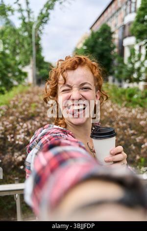 winking redhead woman with curly hair on blue background. Woman ...