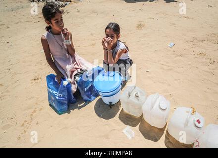 Palestinians carry jerry cans filled with water distributed by a water ...