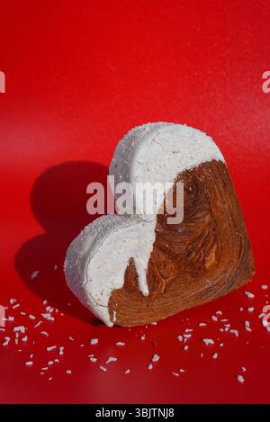Heart shaped coconut flavor croissant on red background with copy space ...
