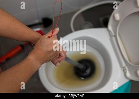 A woman's hand is using an air pump to solve a clogged toilet Stock ...
