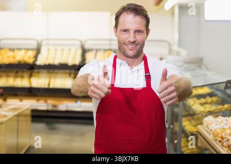 Baker man wearing a red apron standing in a wheat field and holding ...