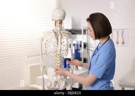 Doctor pointing at parts of human skeleton model in clinic Stock Photo ...