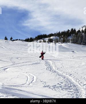 Girl on a snowboard in a snowy mountain couloir among a snow covered ...
