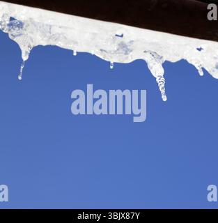 Roof with snow cornice and icicle at wooden house with balcony and ...