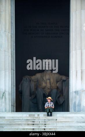 A National Park Service employee and the Lincoln Memorial are reflected ...