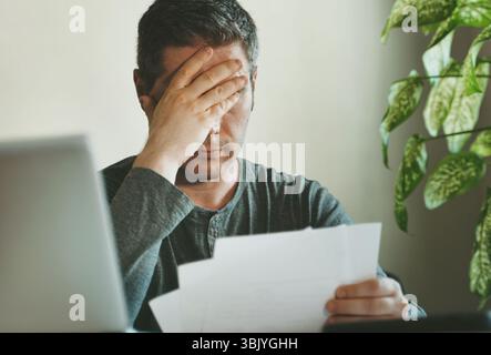 Sad man working with papers at home Stock Photo - Alamy