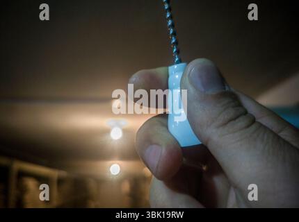 Hand pulling a light porcelain chain light switch attached to the ...