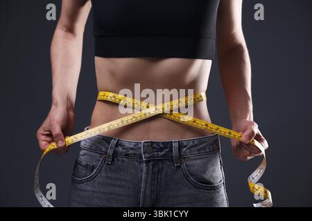 Anorexic woman measuring her waist on grey background, closeup Stock ...