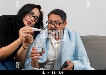 Asian man holding thermometer and water with pills for sickness Stock ...