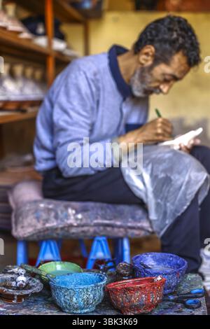 Worker painting dishes in a pottery workshop, Safi, Morocco. Worker ...