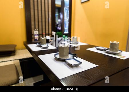 Large table in japanese restaurant with yellow interior Stock Photo - Alamy