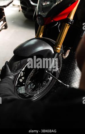 Mechanic performs front suspension service on motorcycle, adjusting ...