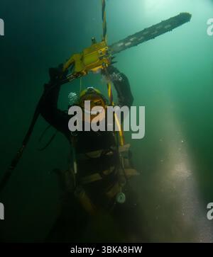 Commercial diver cutting log underwater with chainsaw closeup Stock ...