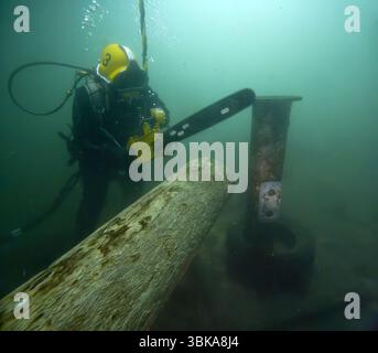 Commercial diver cutting log underwater with chainsaw closeup Stock ...