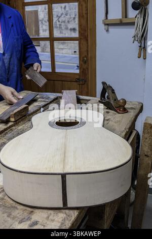 Wood artisan sanding guitar body, creating musical instrument in ...