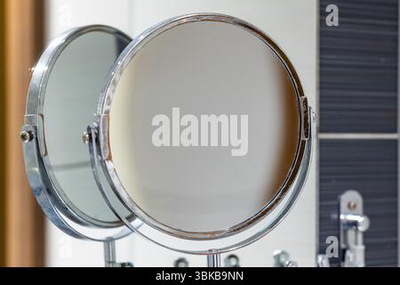 Round bathroom magnifying mirror mounted to the wall with a pantograph ...