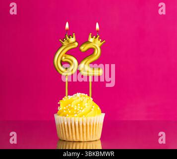 Pink number 62 birthday candle lit on white background Stock Photo - Alamy