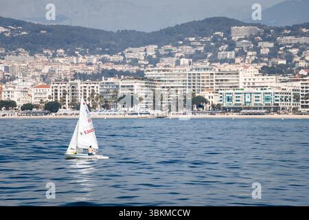 Cannes, France - March 8, 2025: Sailboat on the calm sea with cityscape ...