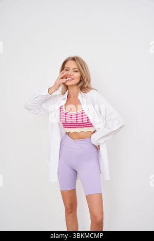 A stylish blonde woman models a chic denim ensemble against a warm ...