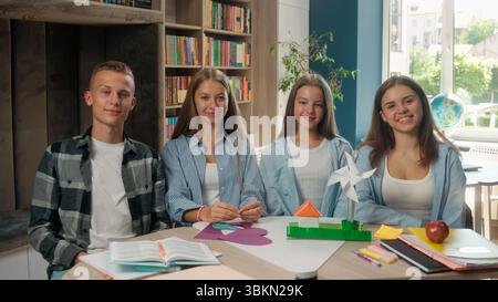 Portrait of four happy teenagers sitting with their mobile phones ...